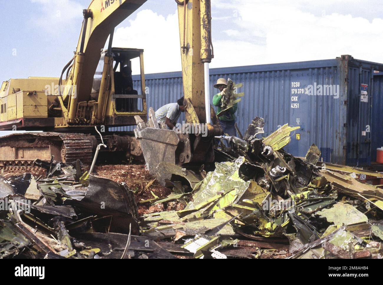 A ditch-digging machine lifts the scrap from a B-52D aircraft, to load ...
