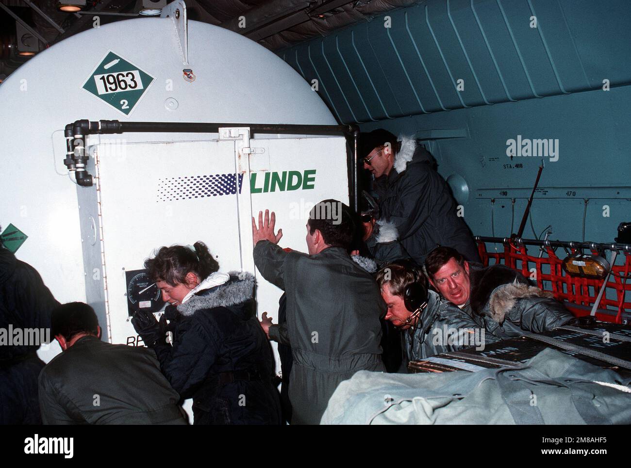 Flight crew and ground crew members pitch in to unload a 20,150-pound ...