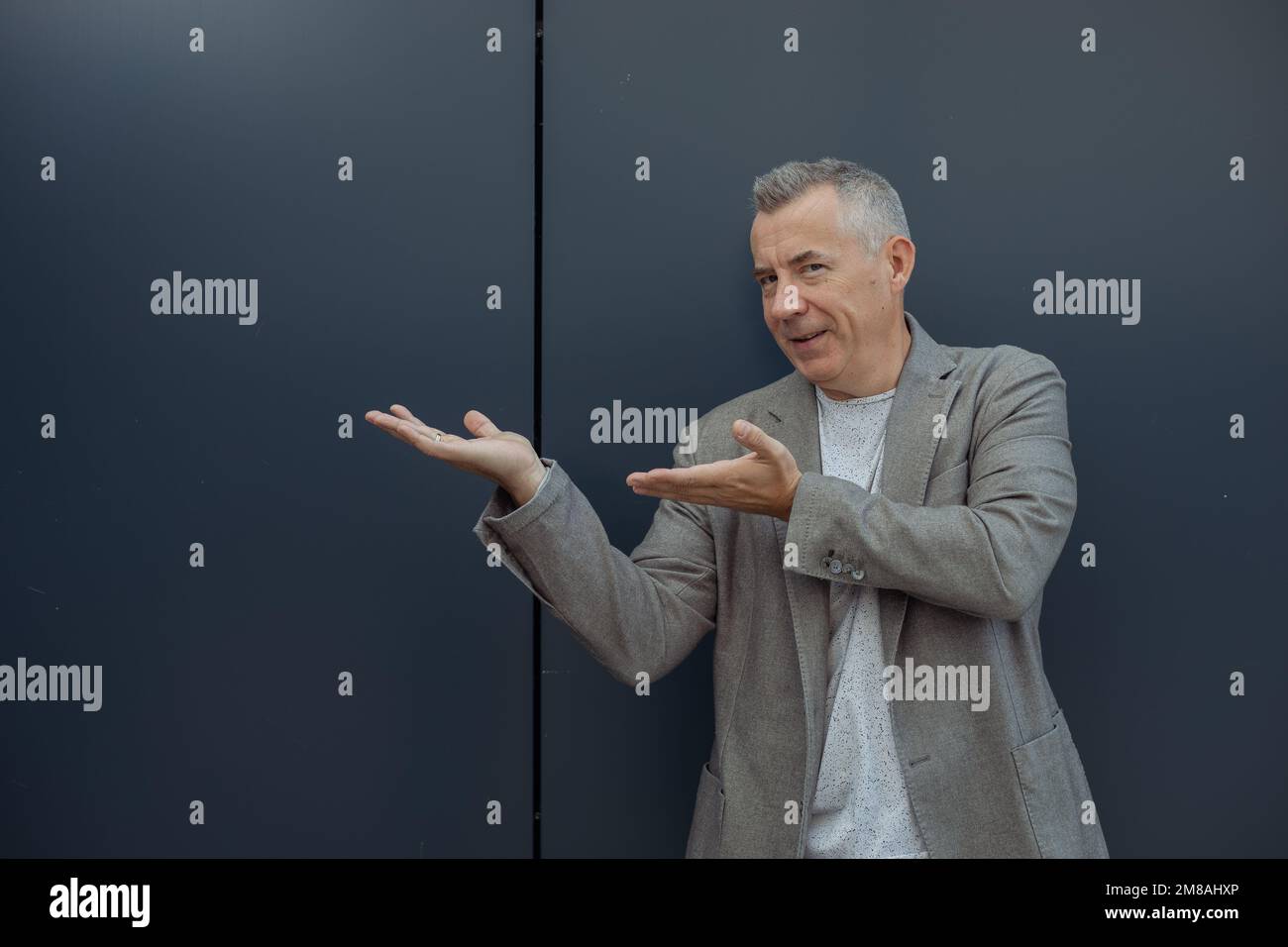 Positive, glad grizzled man holding something empty space on palms ...