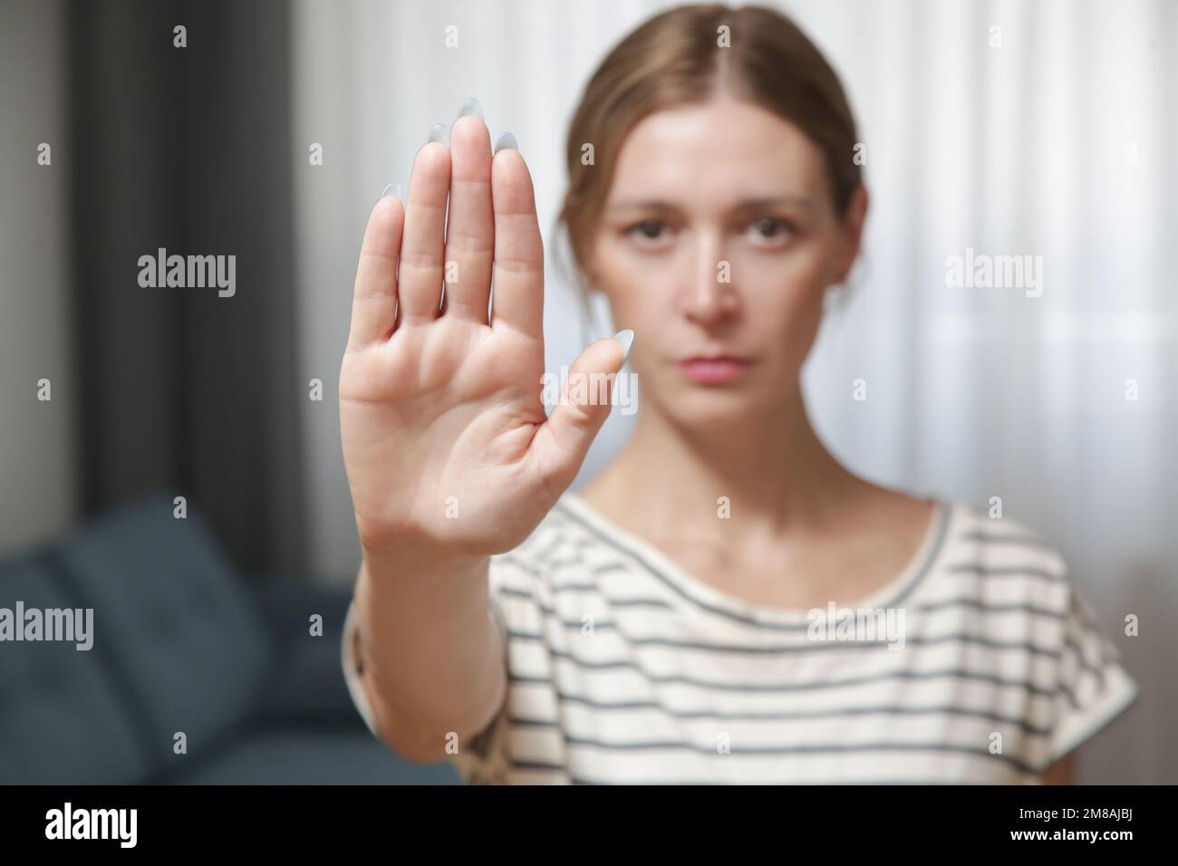 Serious worried young woman making hand stop gesture expressing fighting for equal rights ...