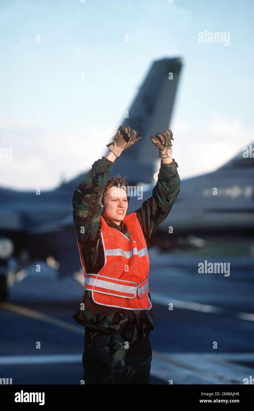An airman signals to a plane on the flight line. Country: Unknown Stock ...