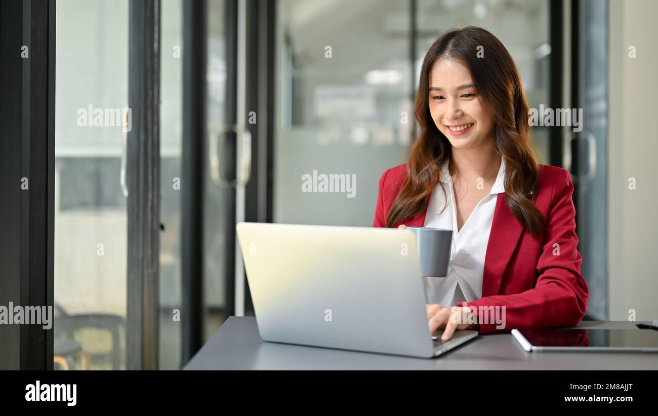 Professional and attractive millennial Asian businesswoman or female manager using laptop ...