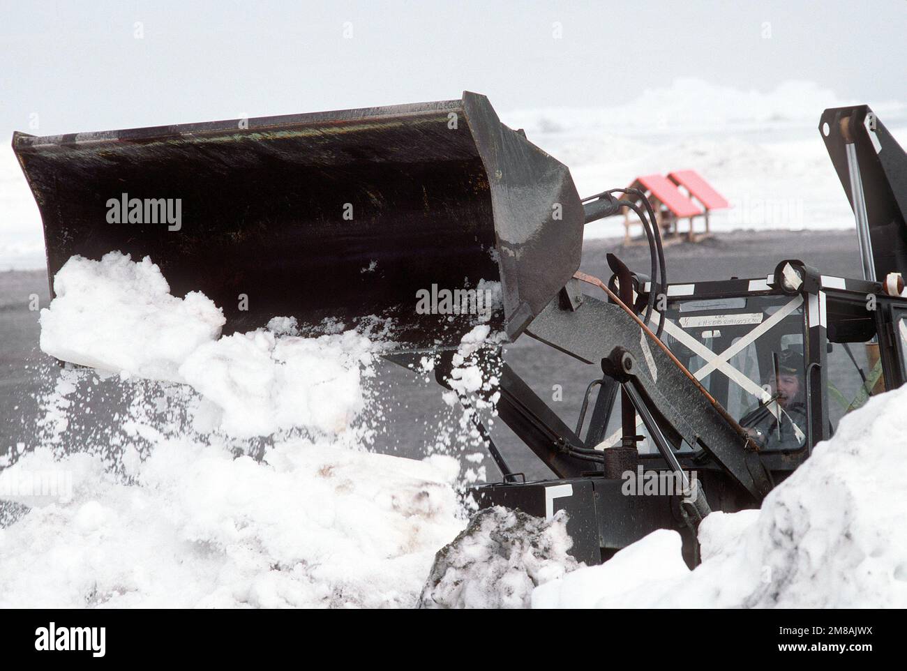 Civilian contract employee Brian Pillars uses a grader to remove snow ...