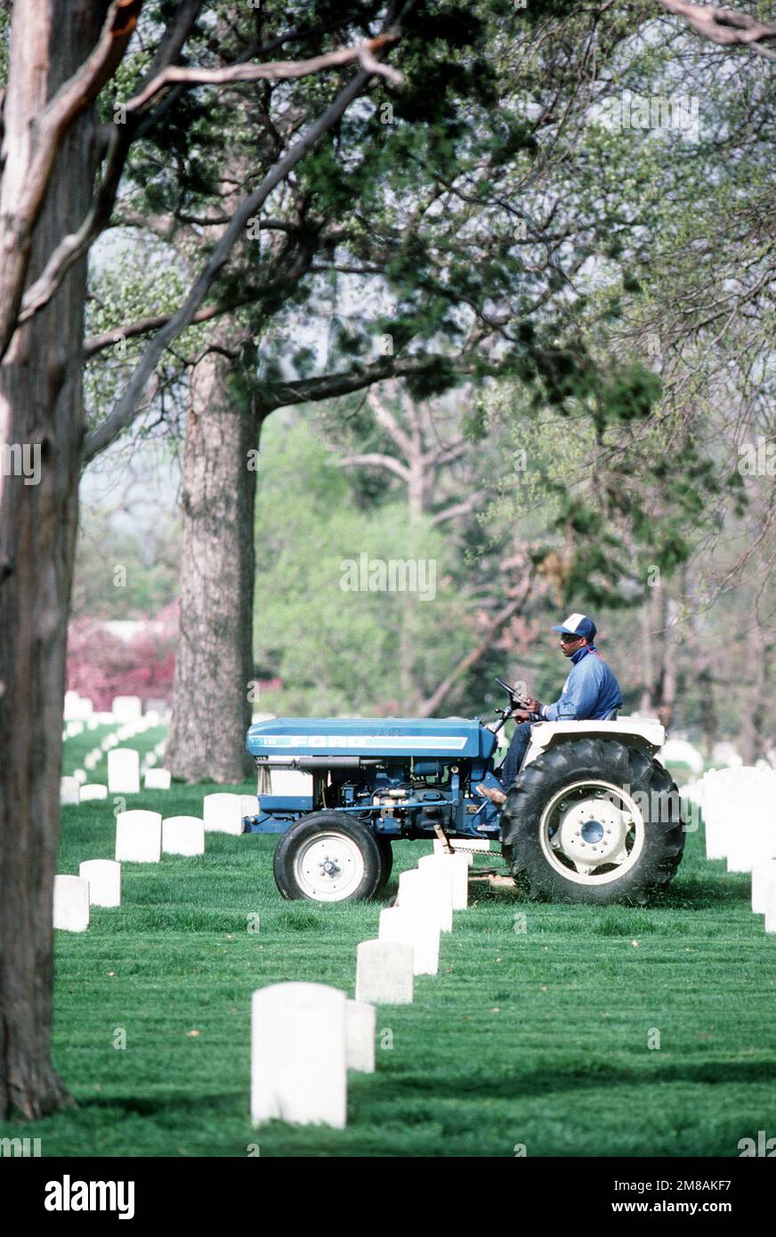 A groundskeeper mows grass between tombstones at the 600-acre Arlington ...