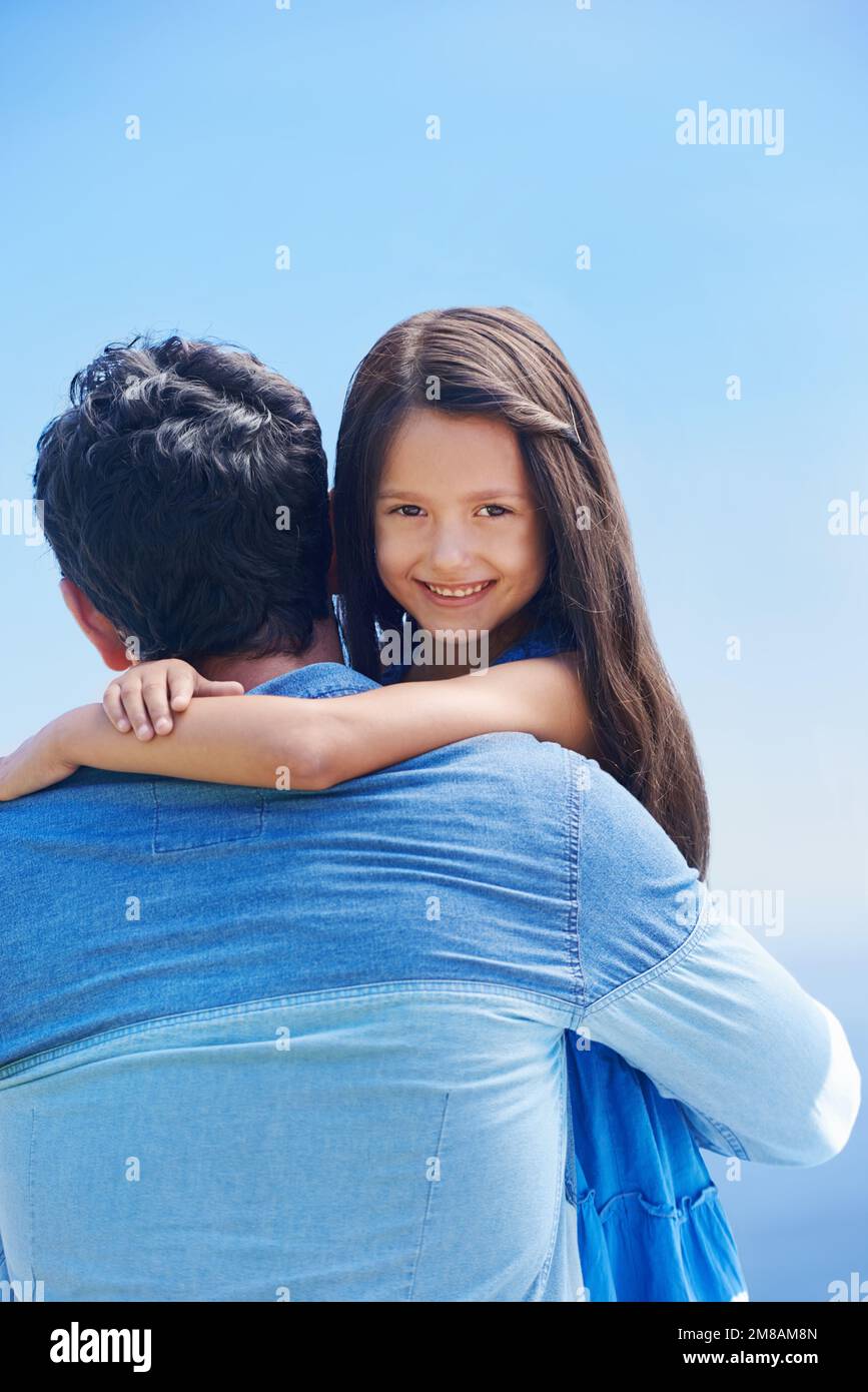 Daddys girl. Portrait of a little girl hugging her father and smiling over his shoulder at the ...