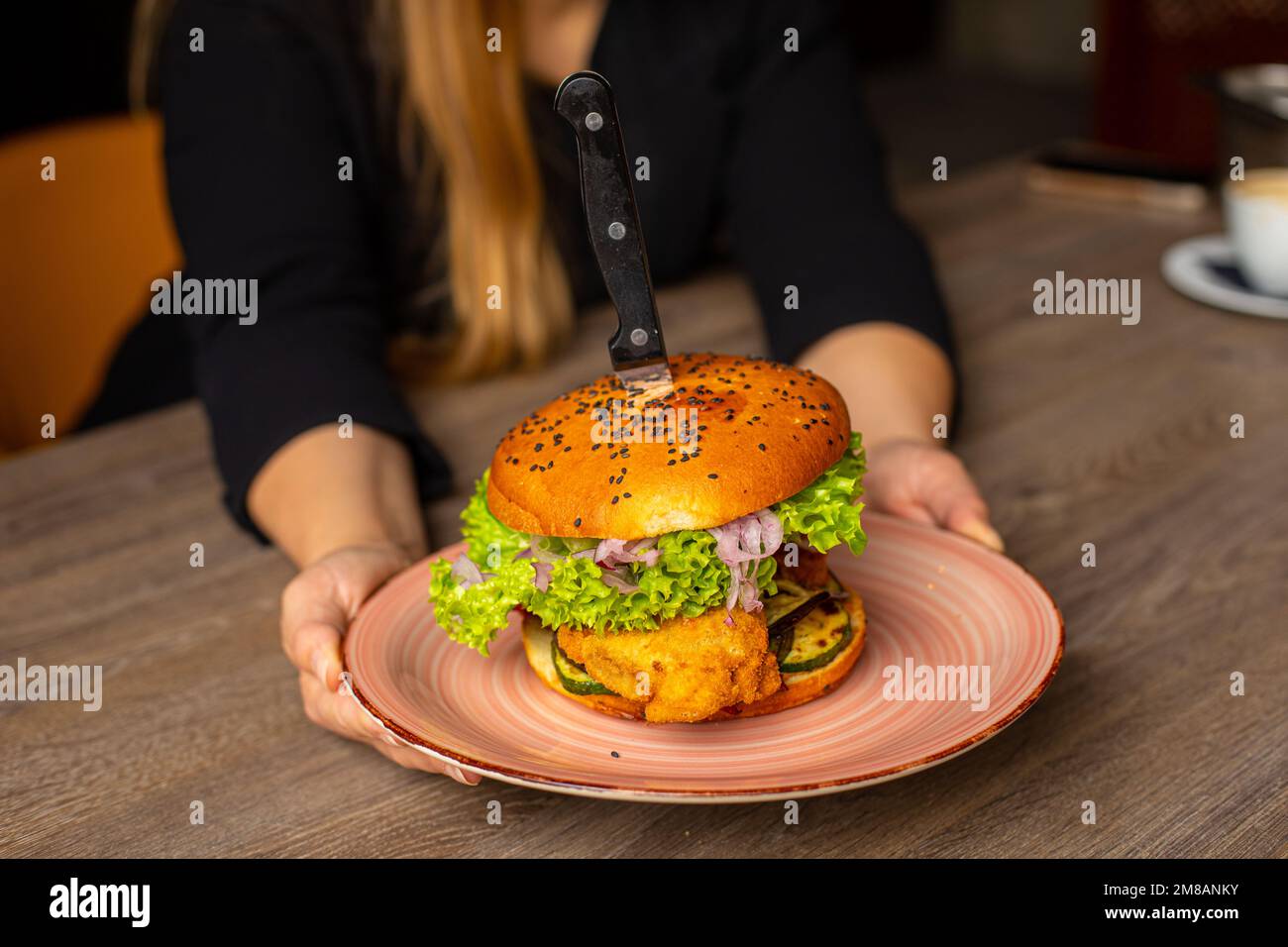 Cropped photo of woman holding plate with burger with lettuce, red ...