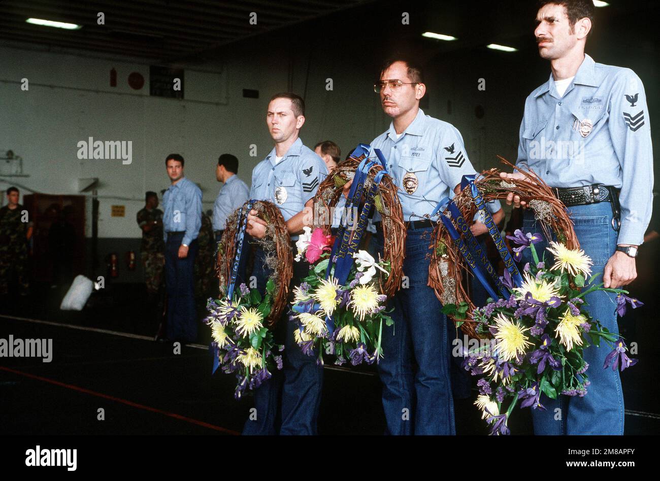 Sailors hold wreaths at a ceremony aboard the amphibious assault ship ...