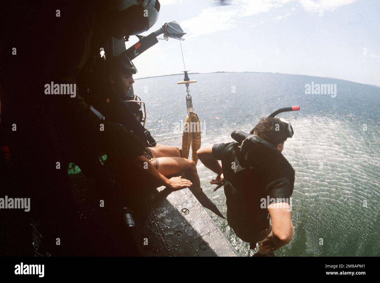 A search and rescue (SAR) swimmer drops toward the water from a ...