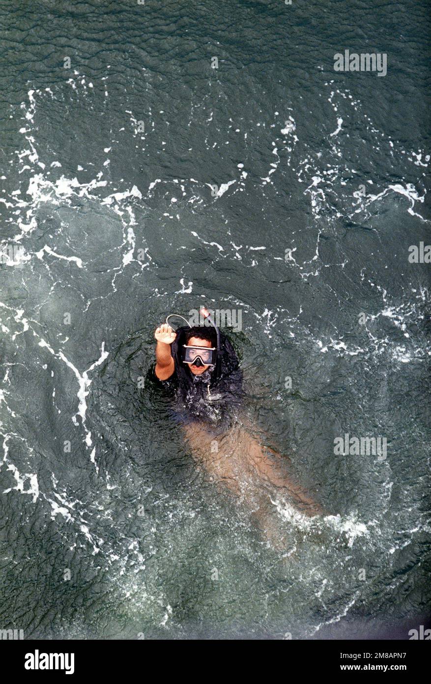 A search and rescue (SAR) swimmer extends his arm as he waits for a ...
