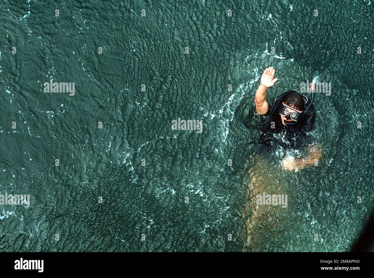 A search and rescue (SAR) swimmer extends his arm as he waits for a ...