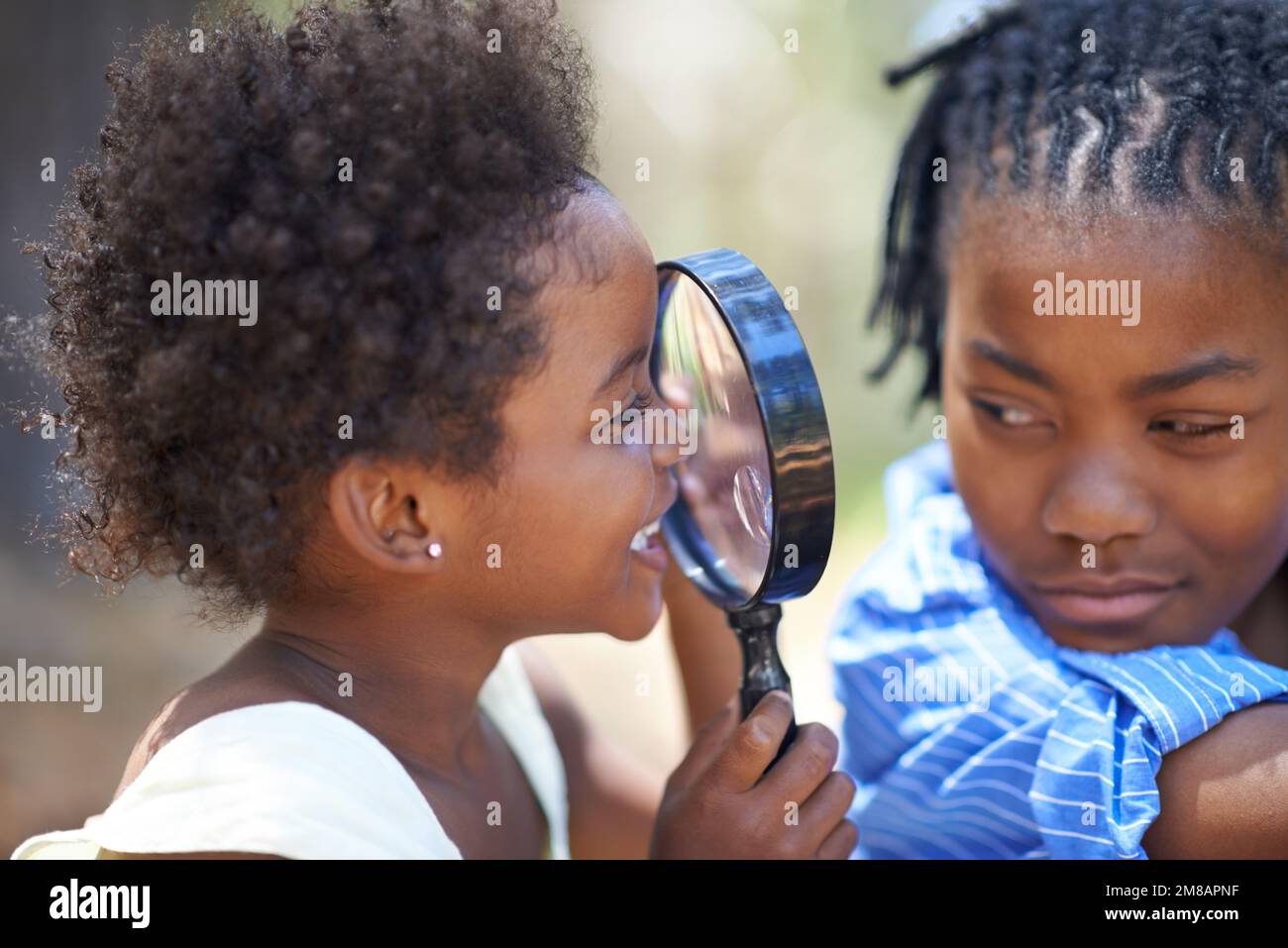 Youve got a huge eye. a brother and sister playing with a magnifying ...