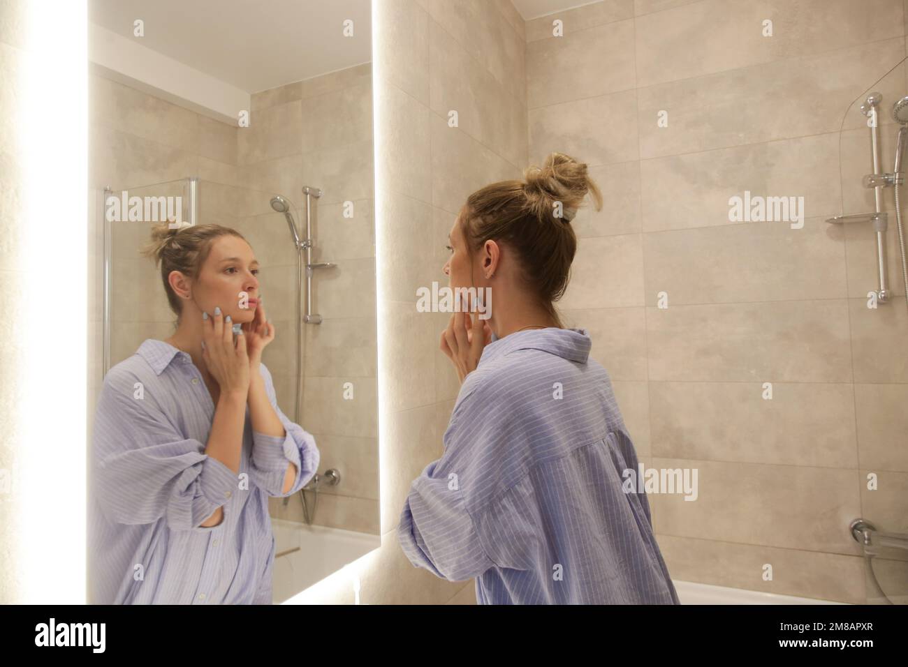 Young woman doing her morning or evening routine in the front of mirror ...