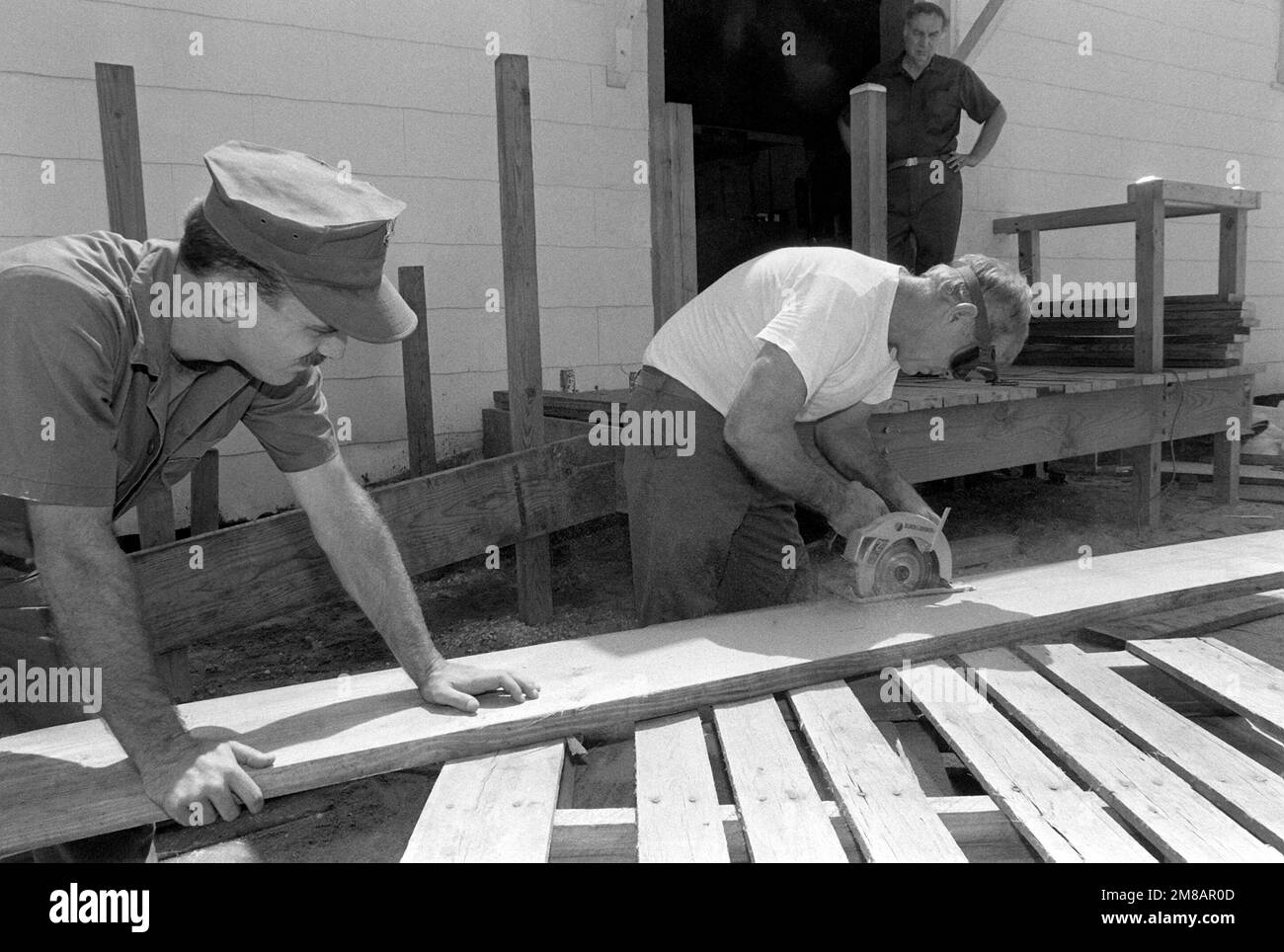 A member of the 1ST Light Division uses a circular saw to cut a plank ...