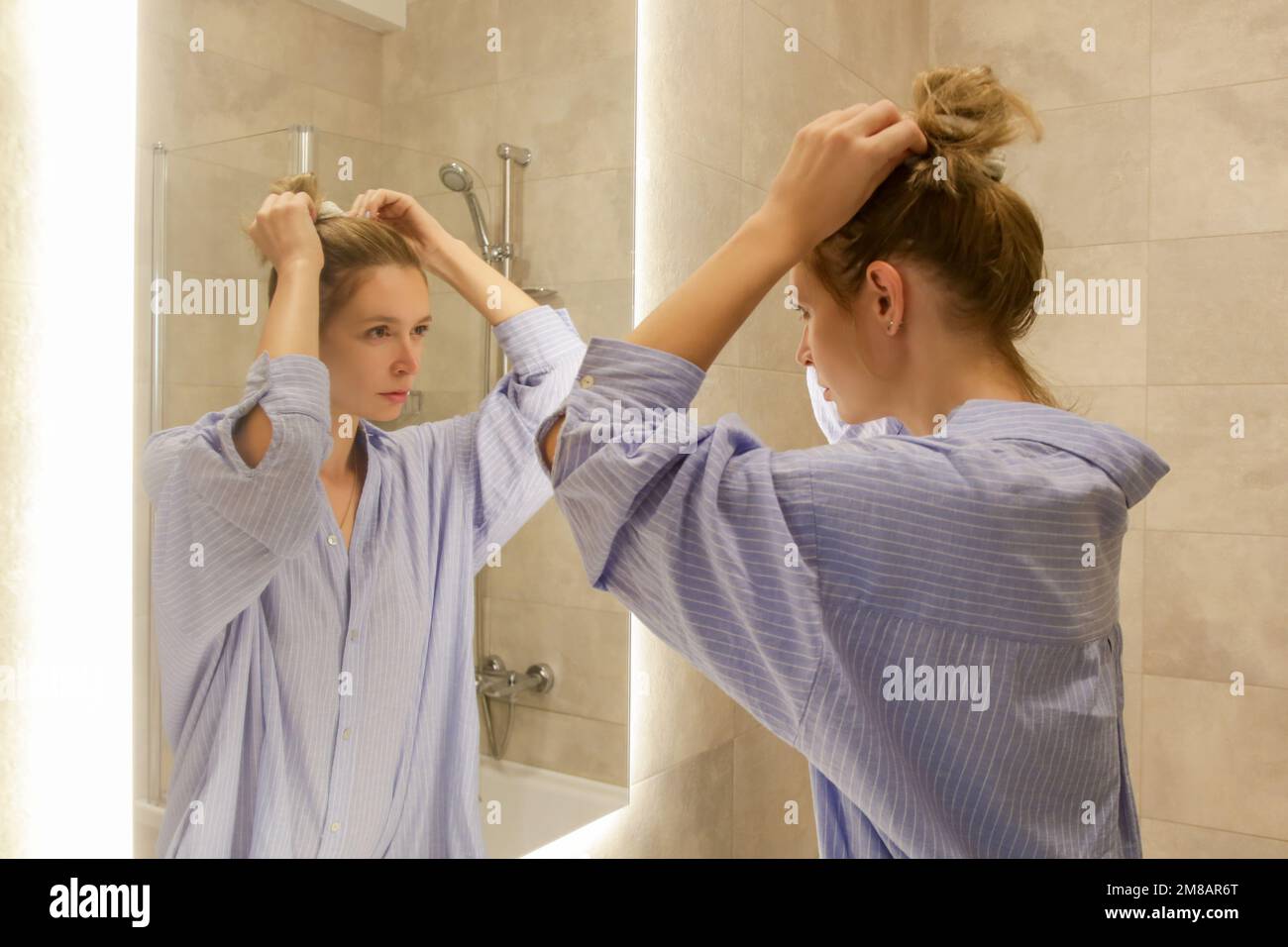 Young woman doing her morning or evening routine in the front of mirror ...