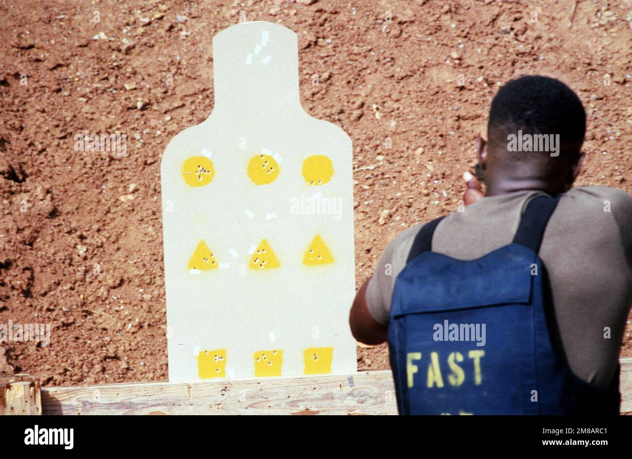 A Marine with an M9 9 mm pistol engages a target on a combat pistol ...