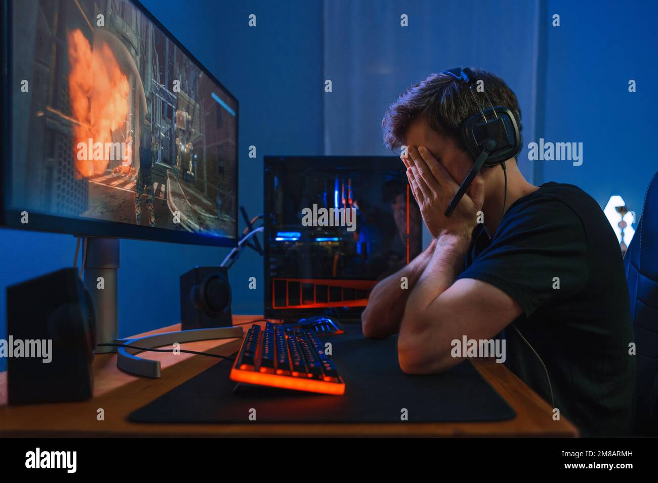 Young caucasian esport gamer wearing headphones feel painful and upset because of losing online ...