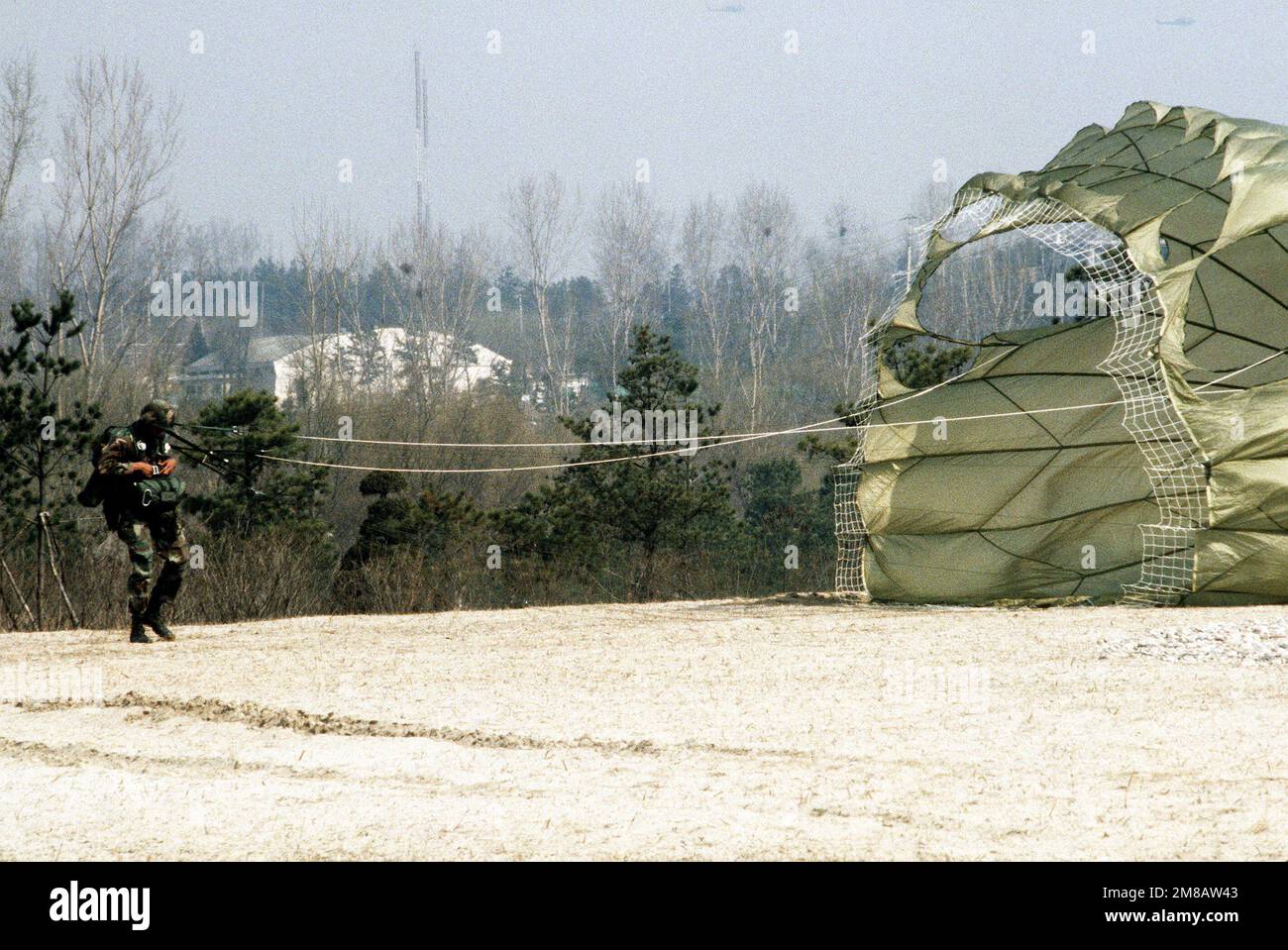An American soldier removes his parachute harness after jumping into a ...