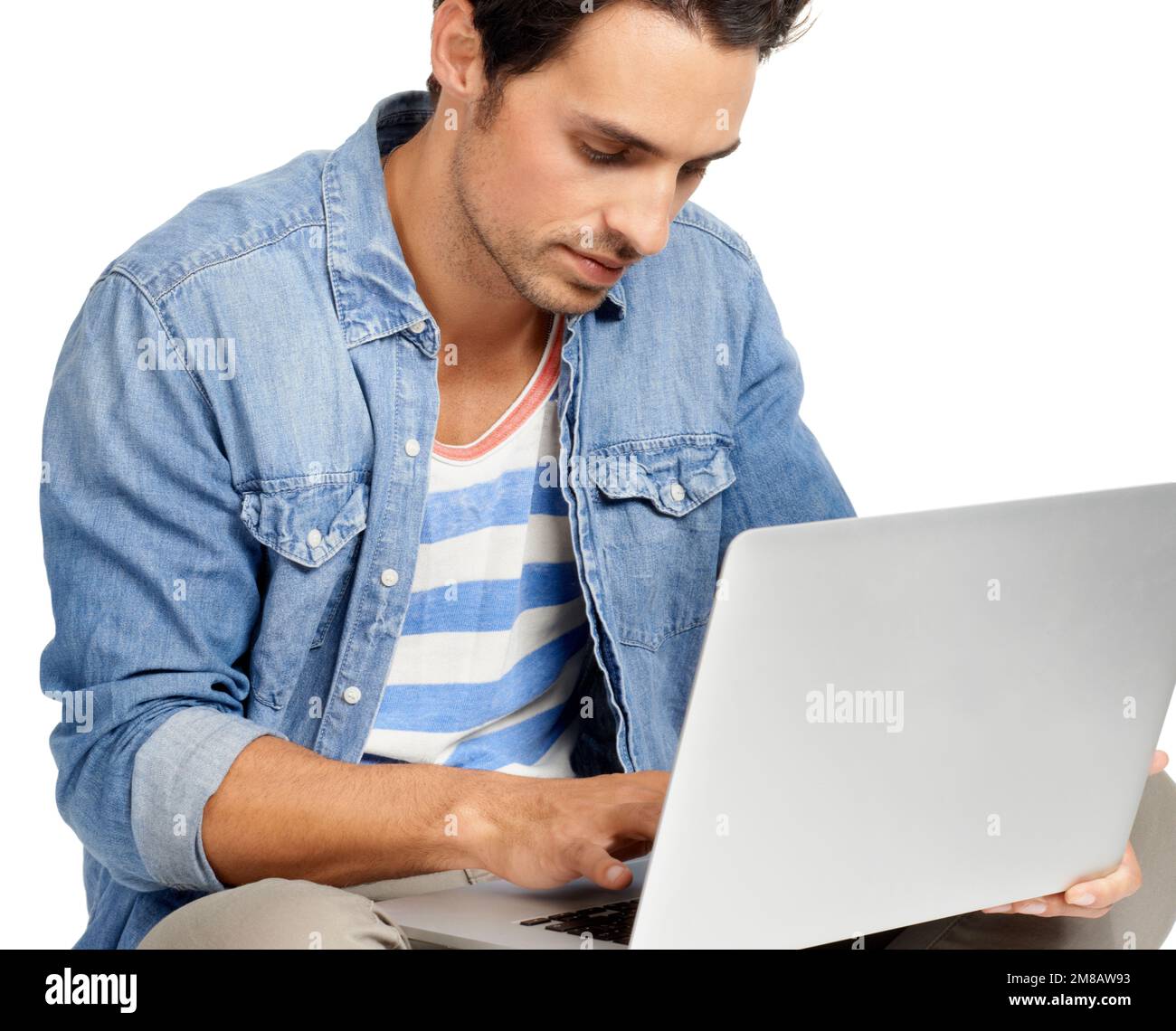 Typing an email. A handsome young man working on his laptop against a ...