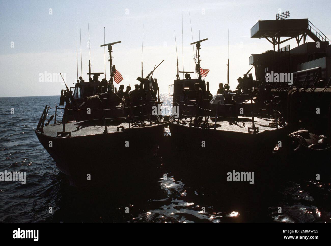 Two PB Mark III patrol boats and their crews are silhouetted by the ...