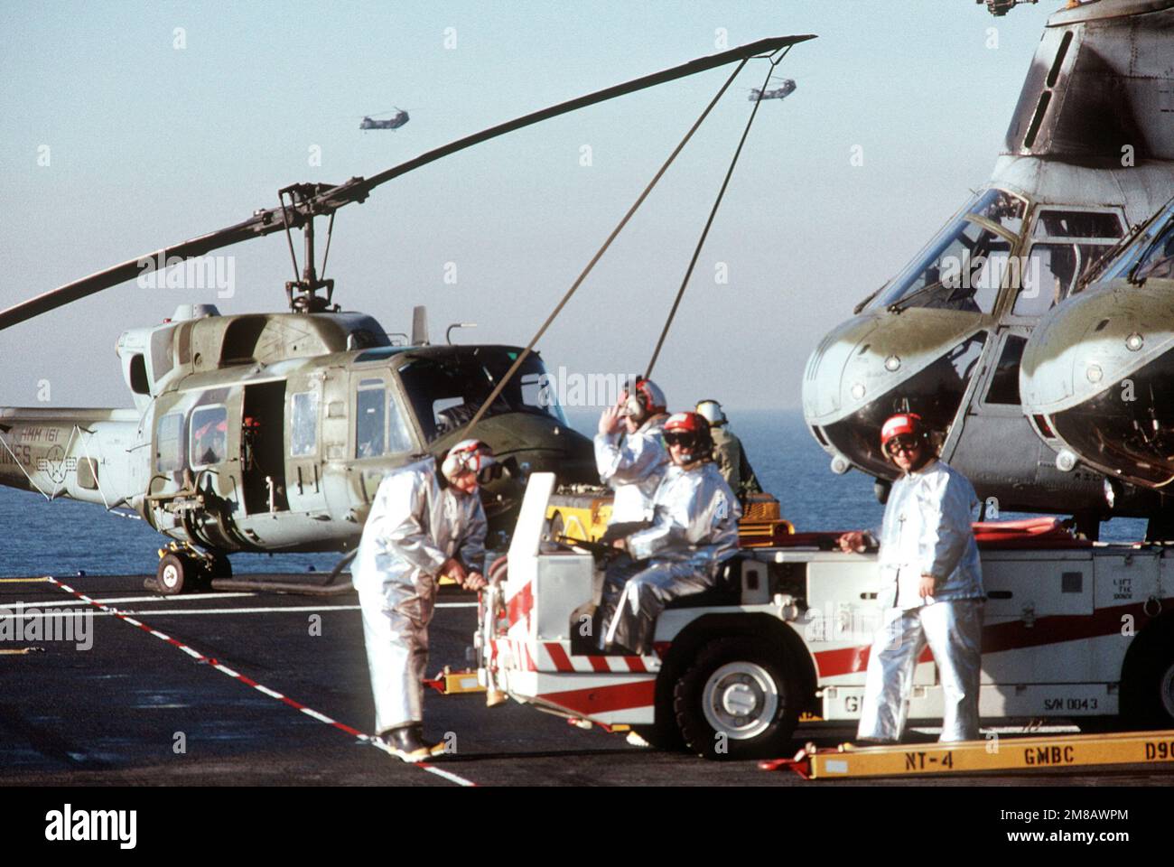 Crash and salvage crewmen dressed in proximity suits stand by on the ...