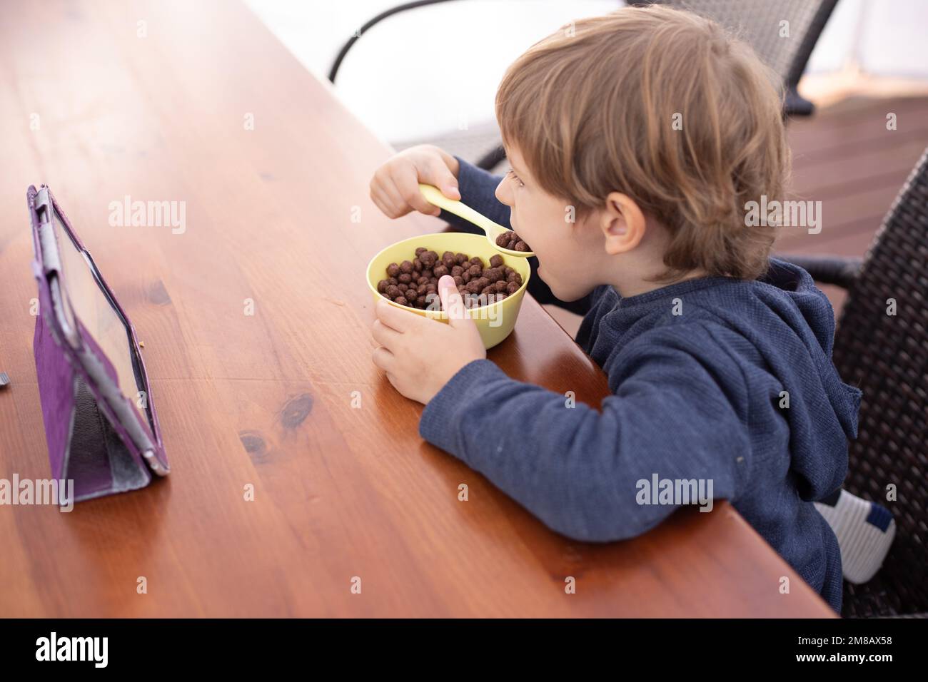 Little boy sit on chair at table and with interest watch cartoon on ...