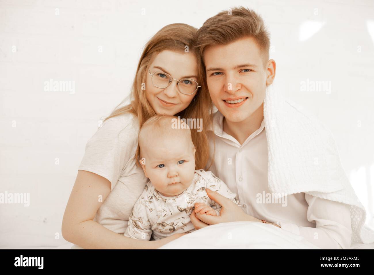 Happy young family of three people sit together and embrace, white ...