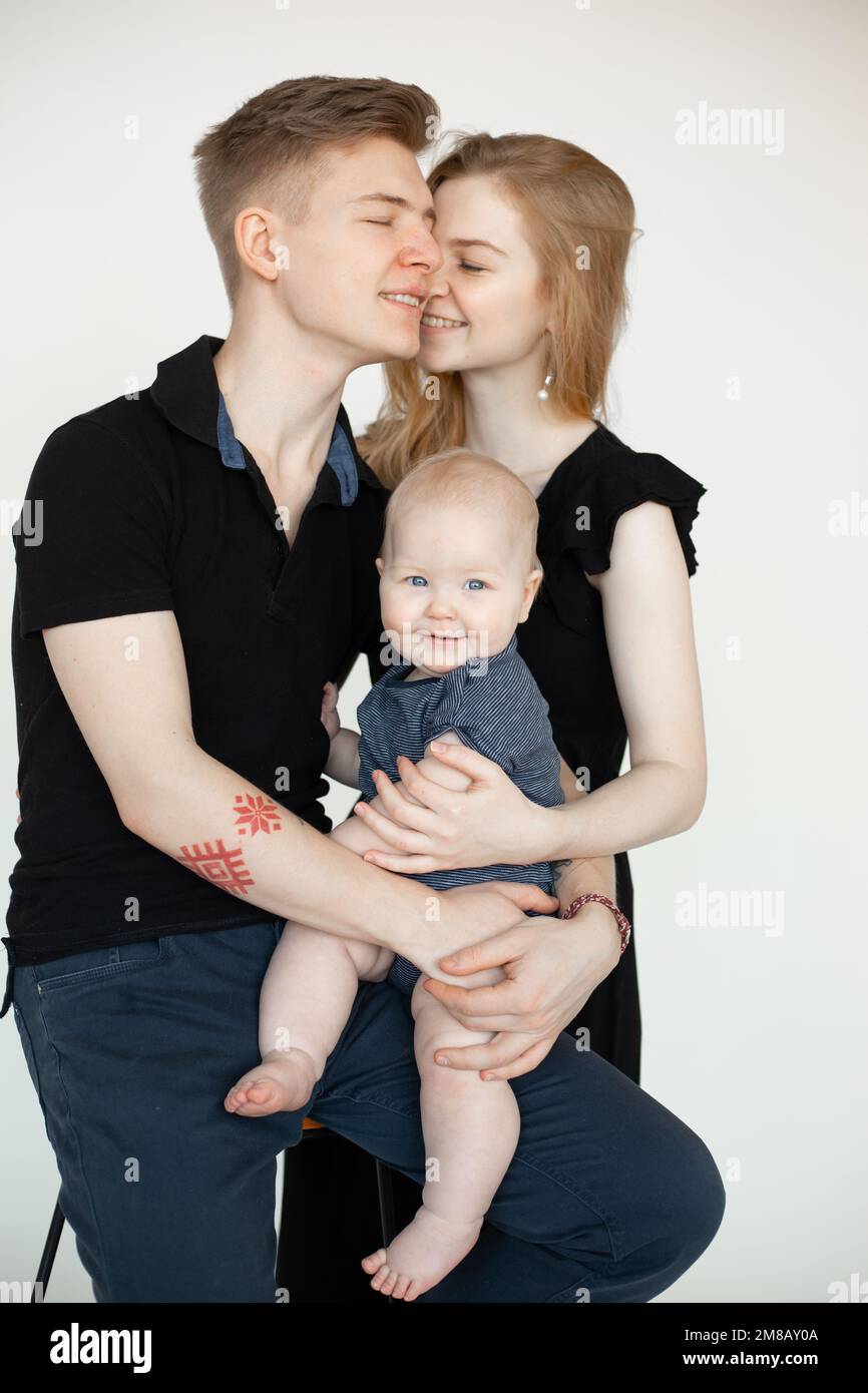 Happy family from three in black looks on white background. Dad sit on ...