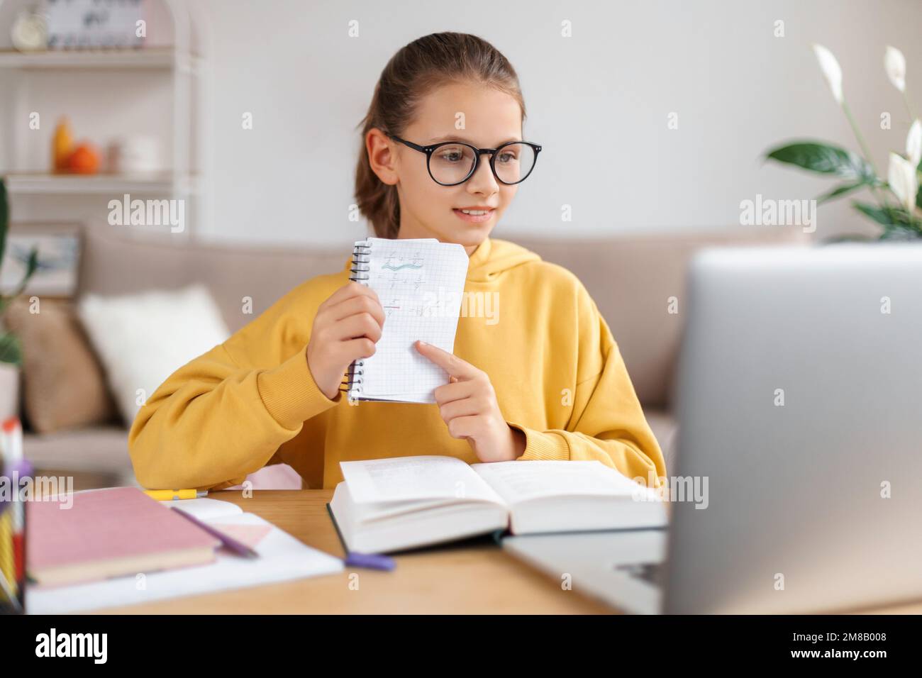 School girl wearing eyeglasses having video call with online tutor ...