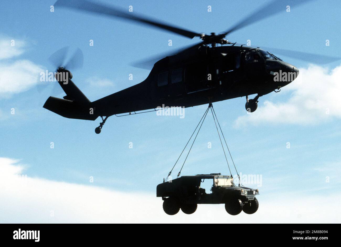 A UH-60 Black Hawk helicopter lifts an M998 high-mobility multipurpose ...