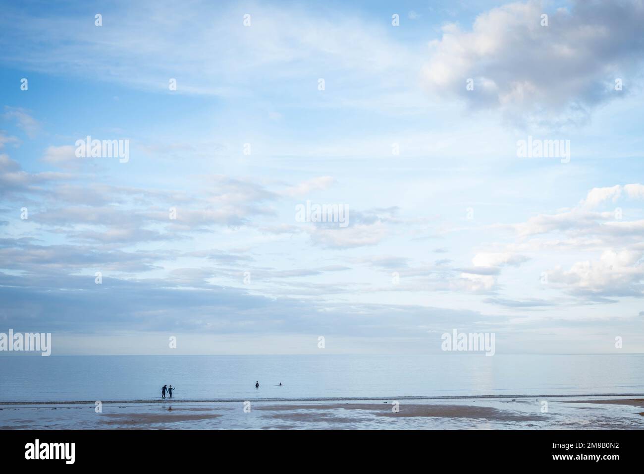 2 silhouetted people dipping their feet in the sea on a deserted beach ...