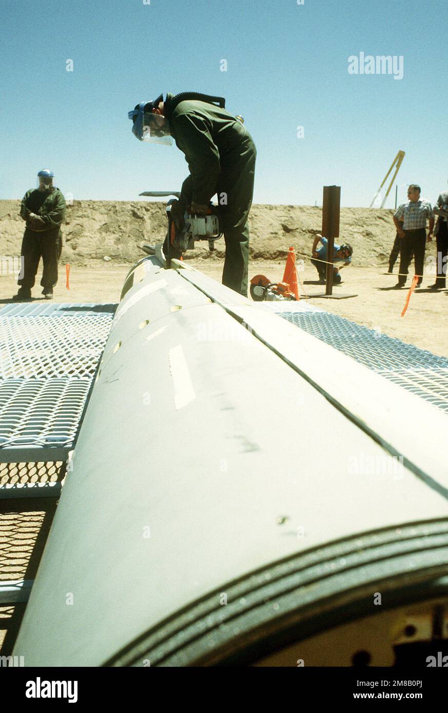 A civilian employee uses a specially-developed saw to cut through a ...