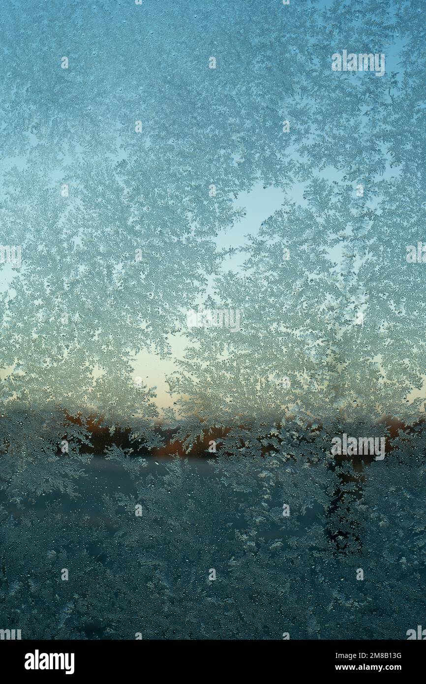 Frost patterns on glass window pane. Frosted glass with blue sky behind ...