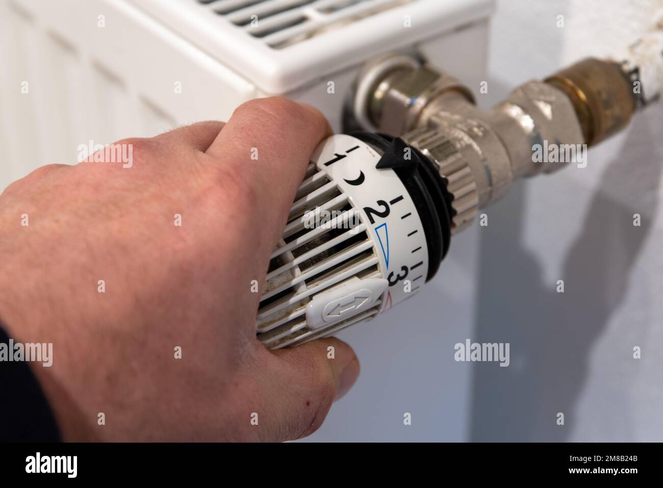 Male hand turns a radiator thermostat Stock Photo - Alamy