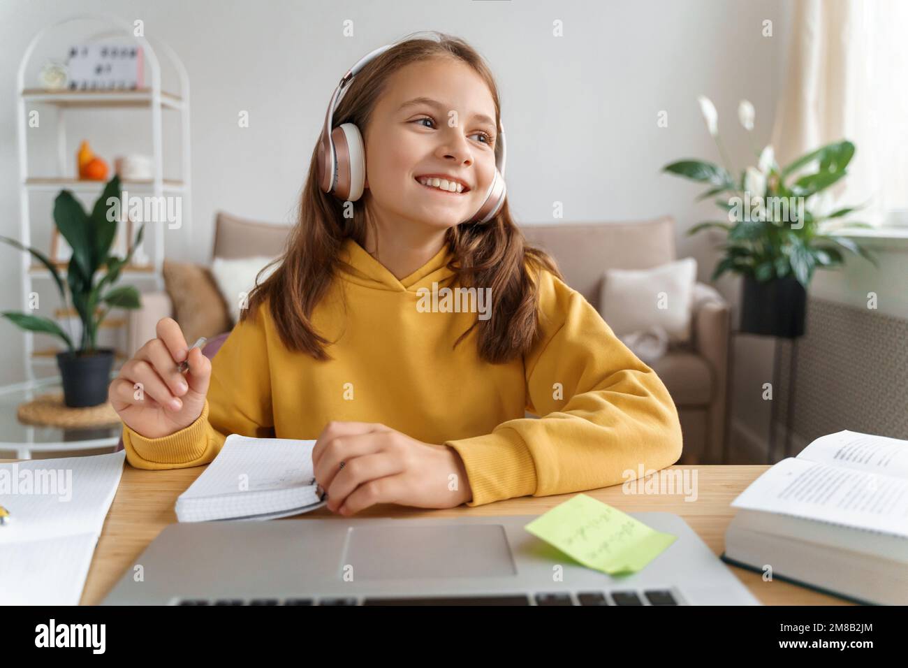 Happy girl wearing headphones using laptop for learning from home ...