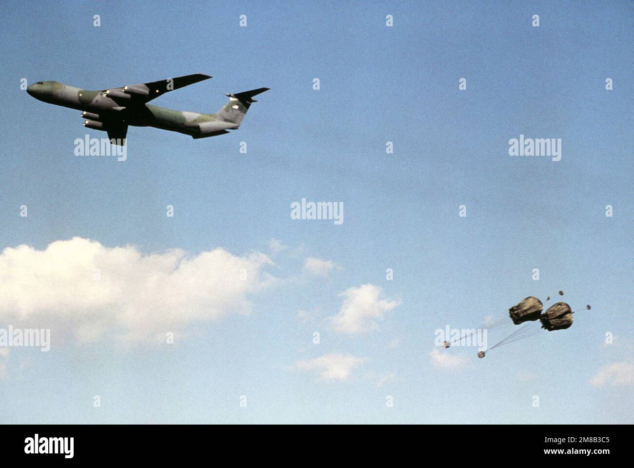 Parachutes open on supplies being dropped from a C-141B Starlifter ...