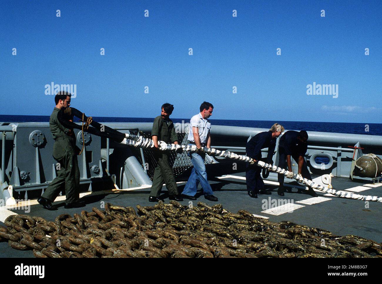 Crew members fake down a tow cable on the deck of the salvage ship USS ...