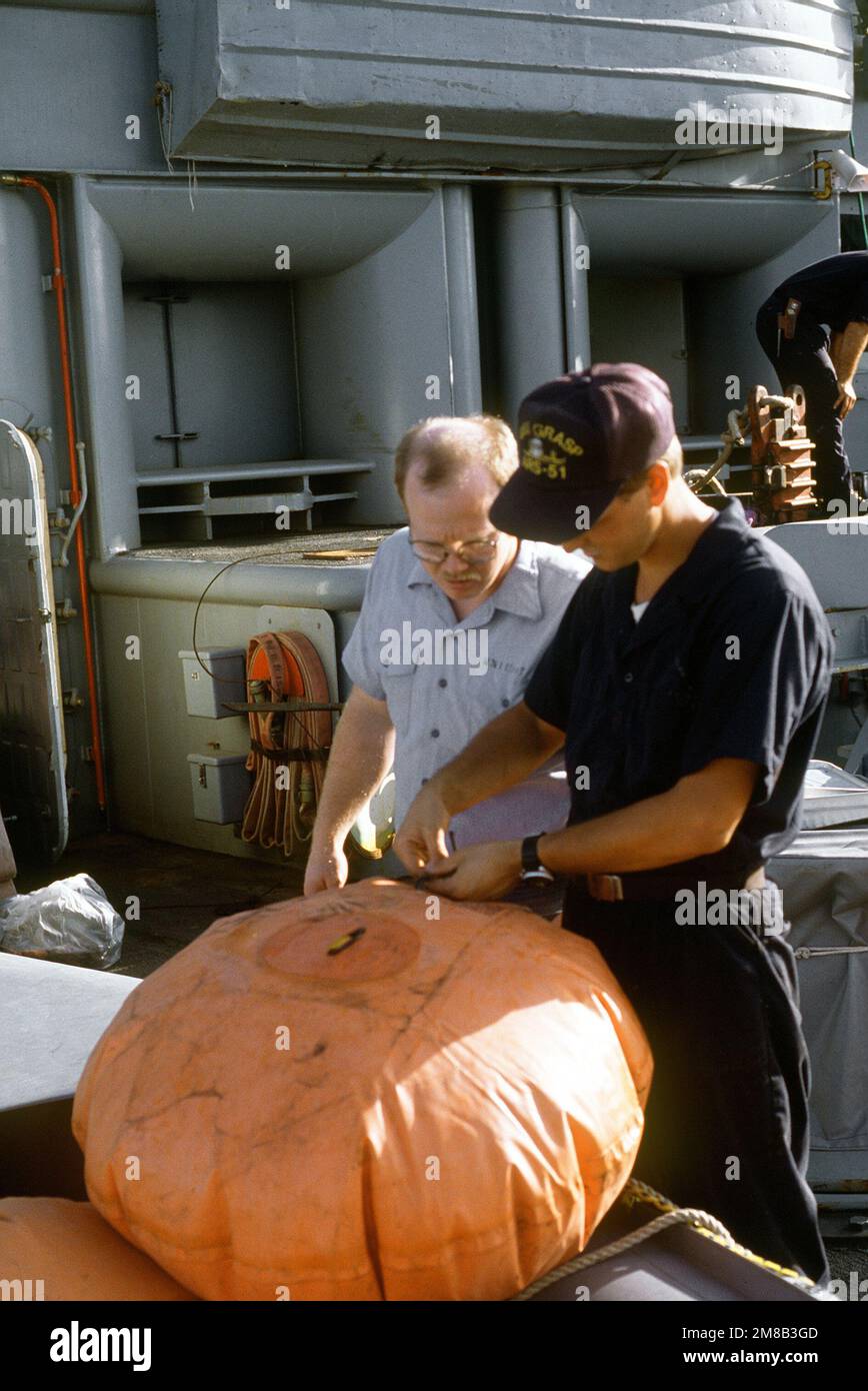 Crewmen prepare marker buoys on the deck of the salvage ship USS GRASP ...