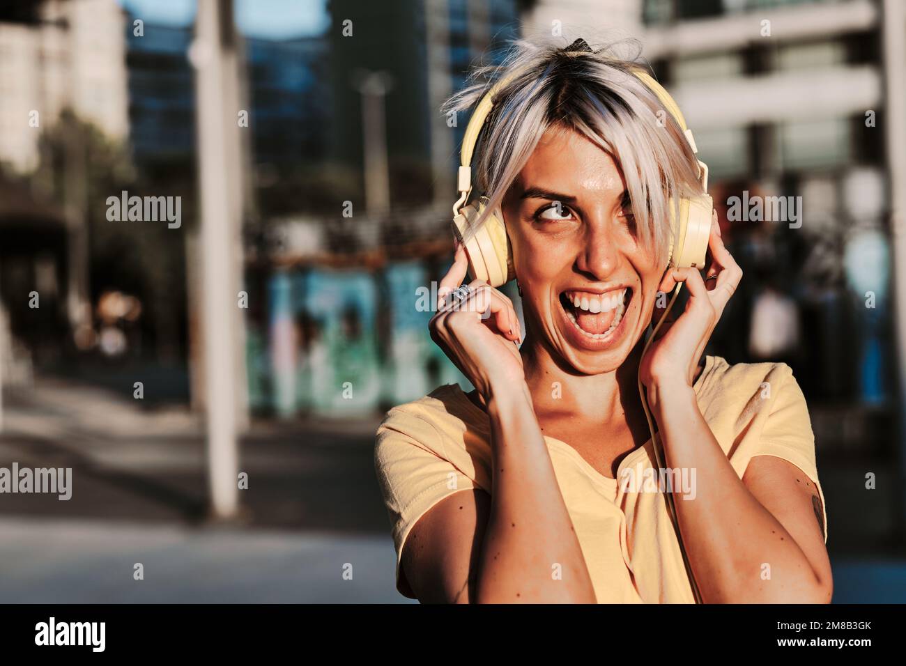 Excited woman enjoying listening to music with headphones outdoors ...