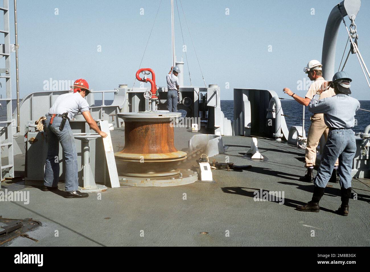 Crew members on the deck of the salvage ship USS GRASP (ARS-51) drop ...