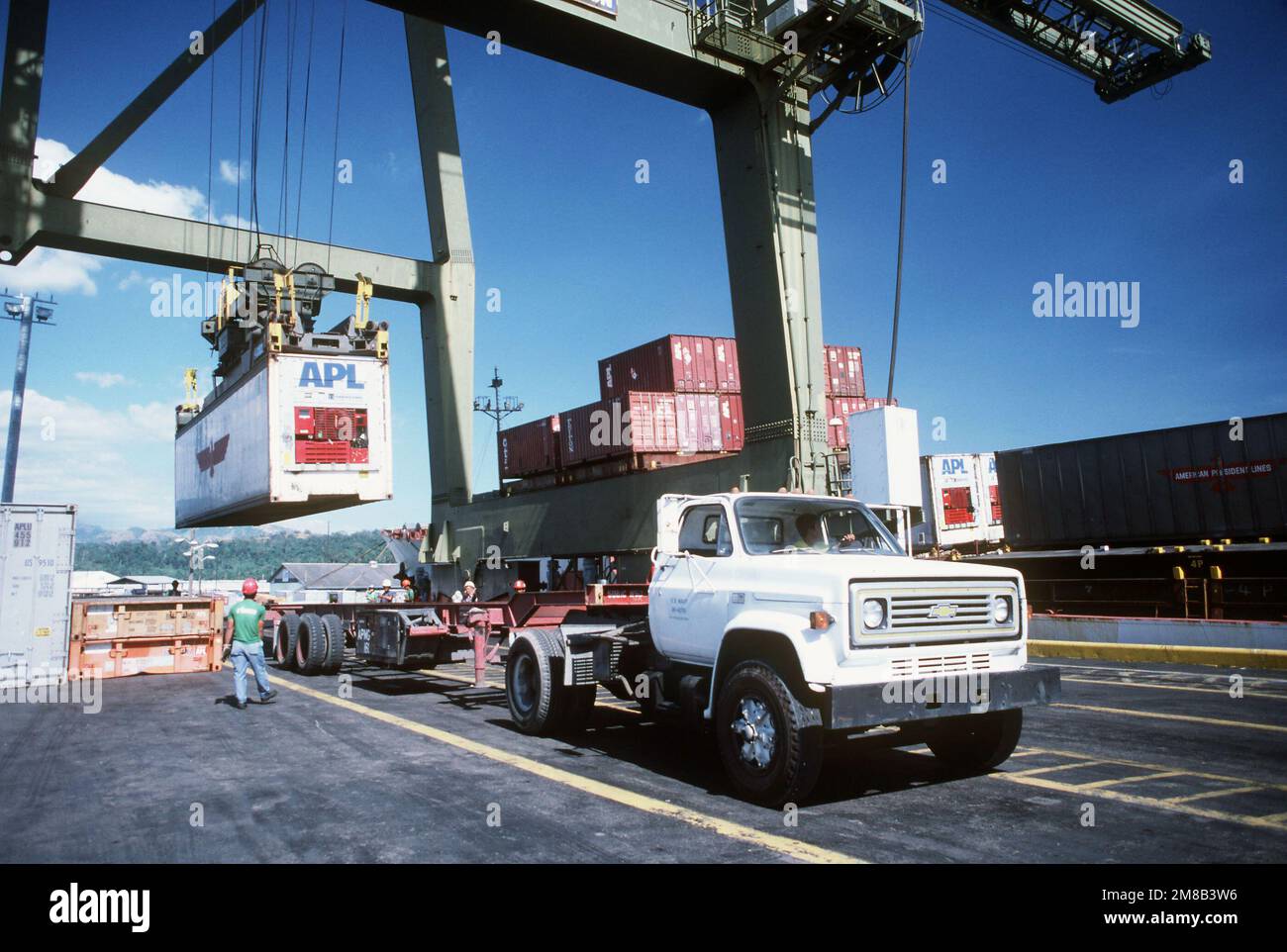 A US Navy truck backs up to position its trailer beneath a container ...