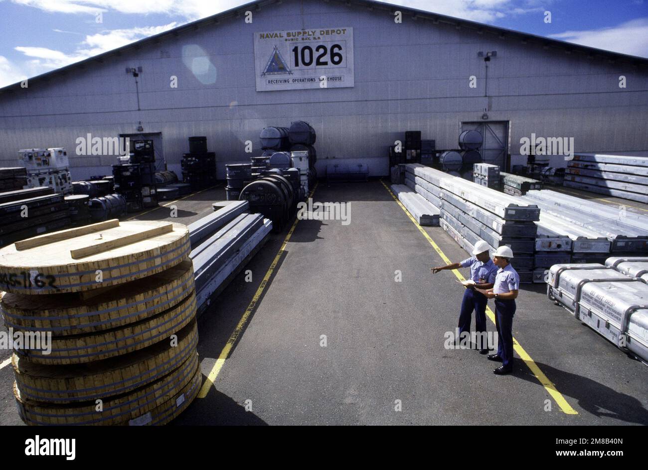 Two sailors take inventory of the crates stacked outside a receiving ...