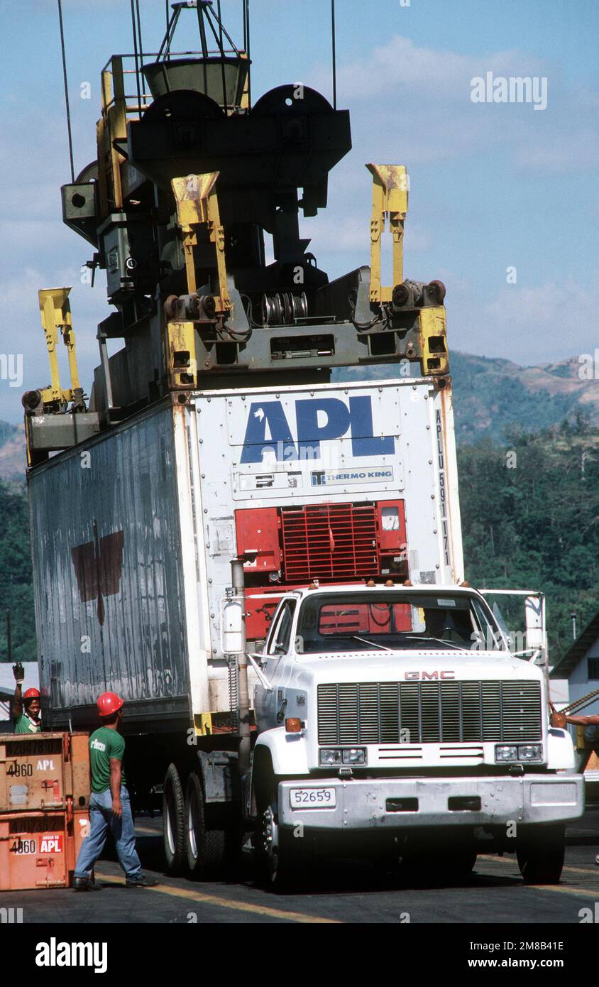 A container unloaded from a ship is lowered onto the bed of a U.S. Navy ...