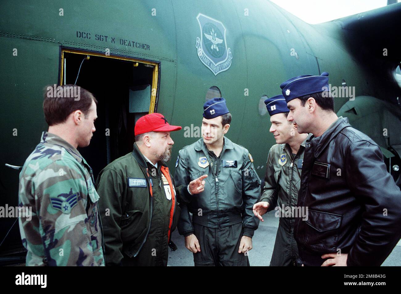 Air Force personnel confer during the loading of a C-130E Hercules ...