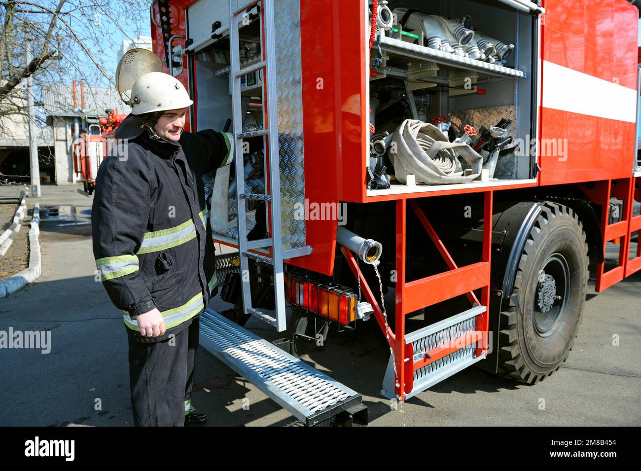 Fireman preparing firefighting equipment near firetruck before ...