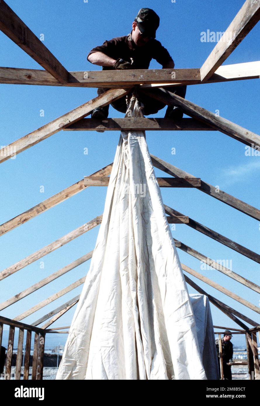 A member of a Prime Beef construction team puts the roof on a structure ...