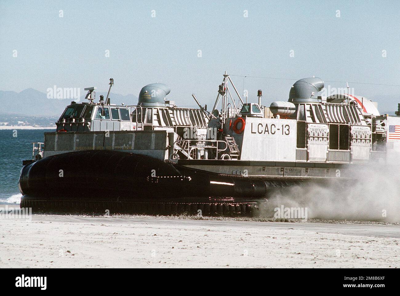 The air cushion landing craft LCAC-13 leaves a trail of blown sand as ...