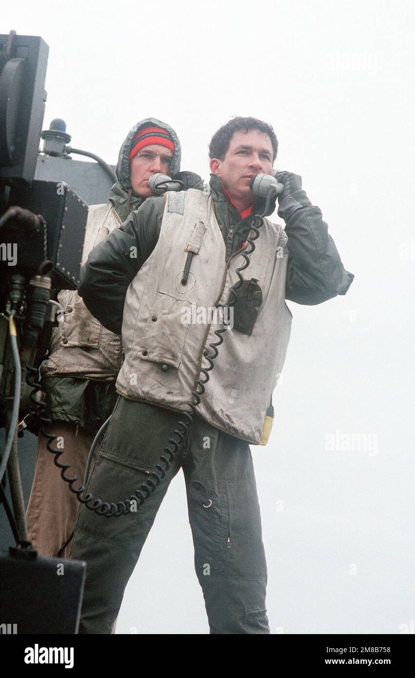 A landing signal officer (LSO) and his assistant monitor the approach ...