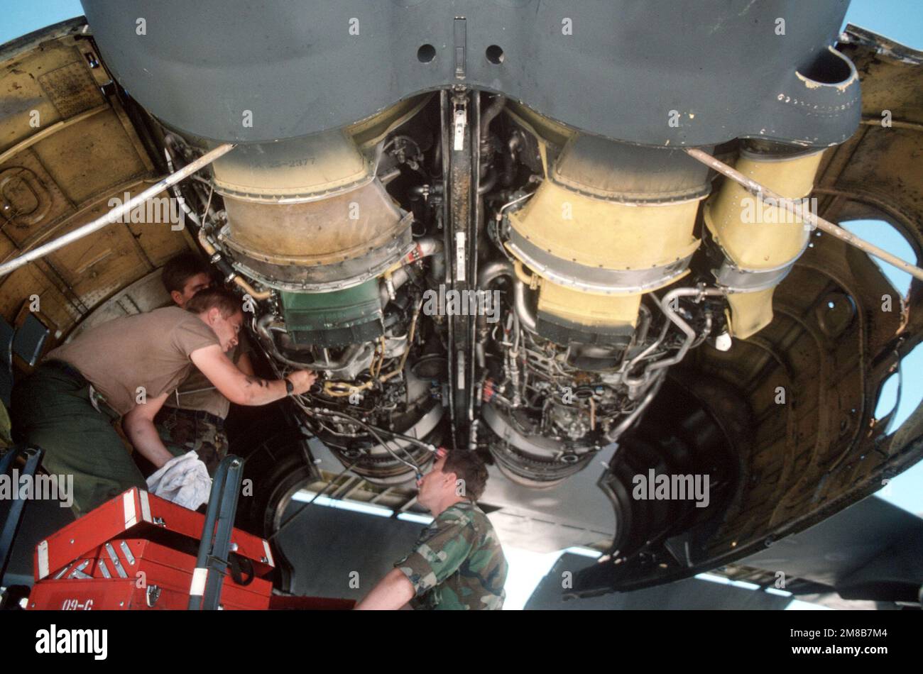 A maintenance team from the 320th Bomb Wing repairs an engine on a B-52 ...