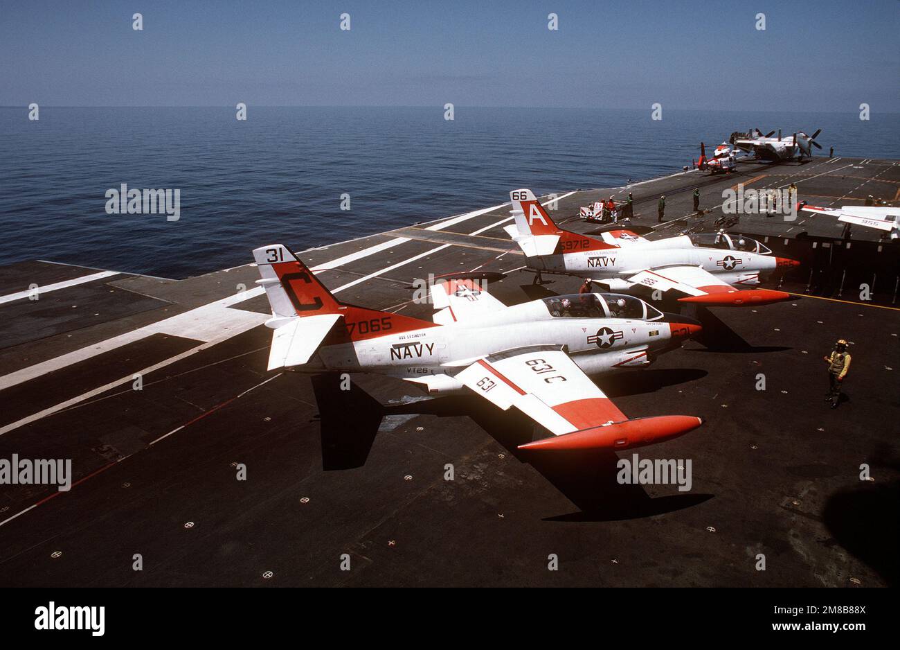 A pair of T-2C Buckeye aircraft wait behind the blast deflector on the ...
