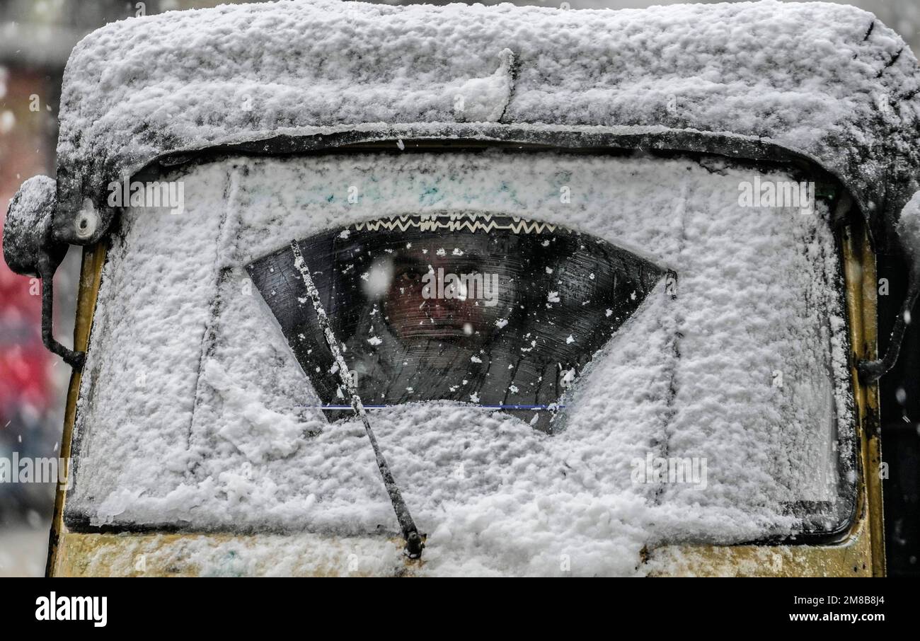 An auto driver looks through a snow-covered windshield in Srinagar ...